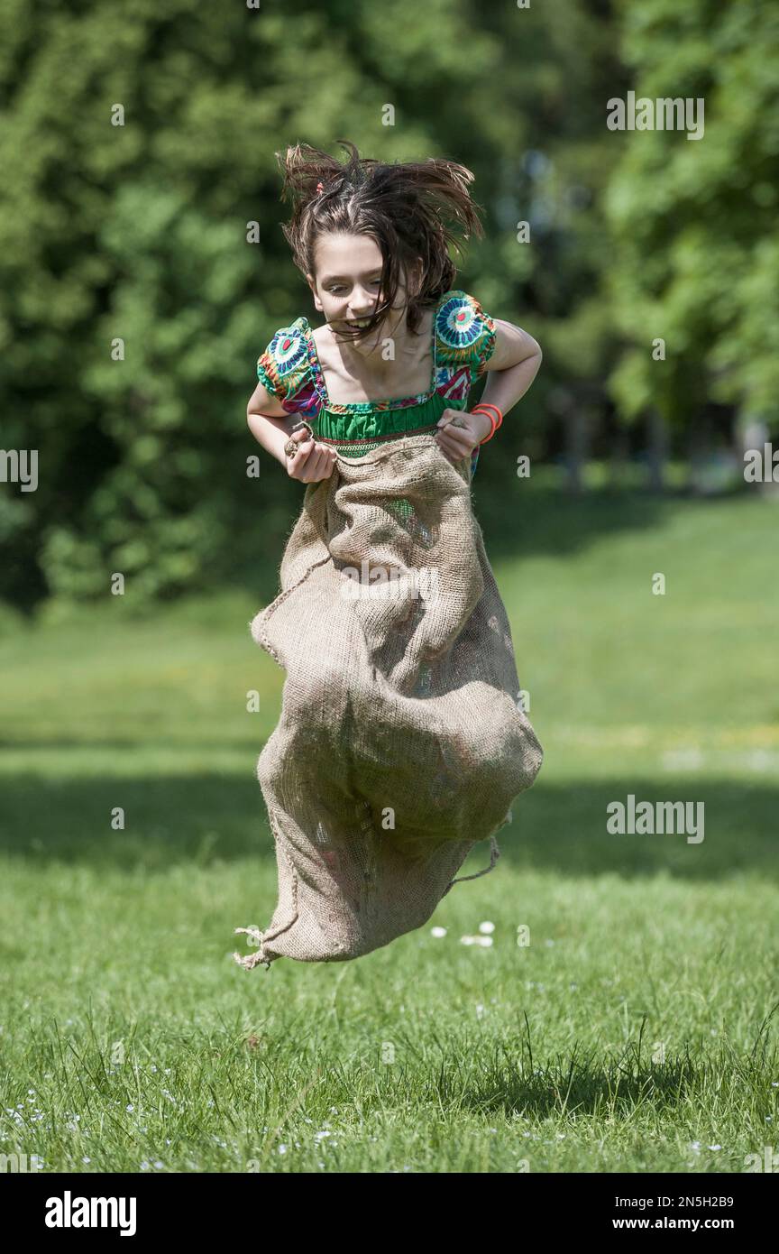 Girl jumping in sack race in a field, Munich, Bavaria, Germany Stock ...
