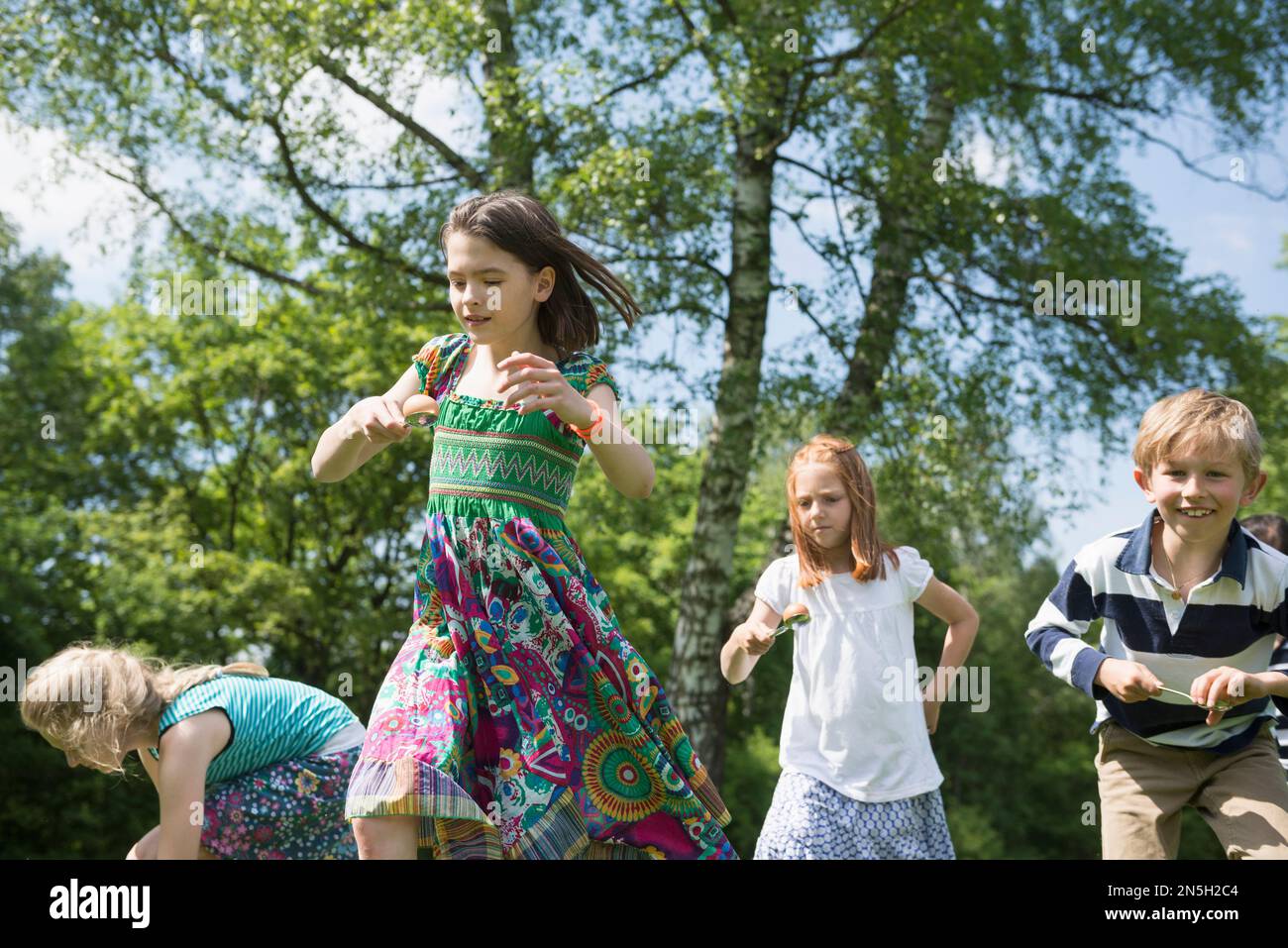 Group of children competing in an egg-and-spoon race in a park, Munich ...