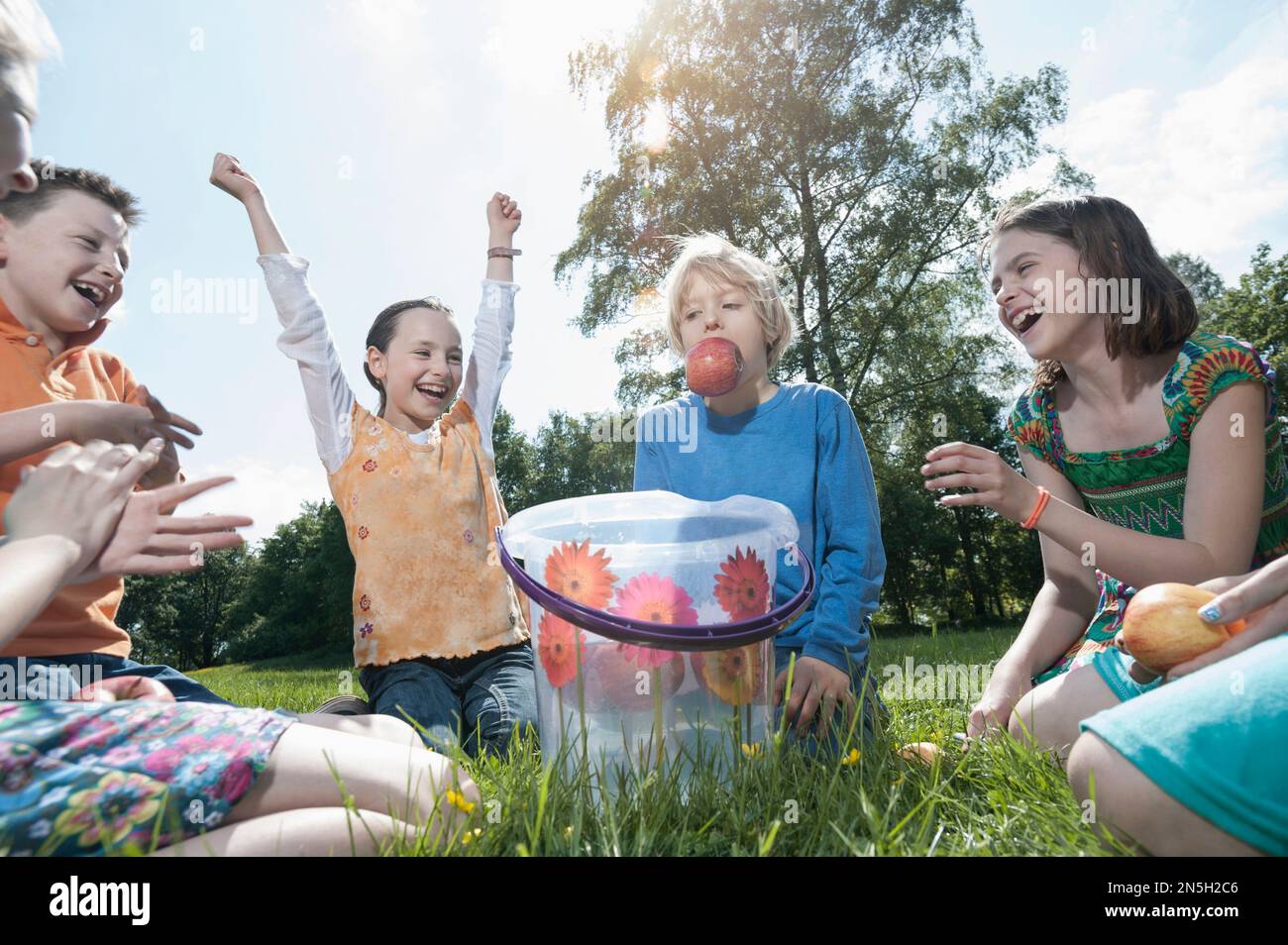 Boy trying to take apple out of a bucket with their mouth, Munich ...