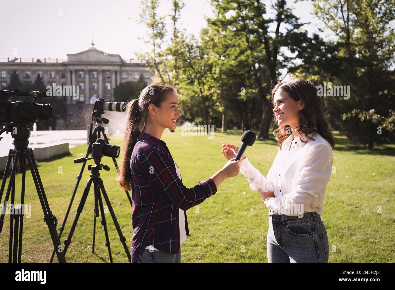 Professional journalist taking interview in front of video cameras ...