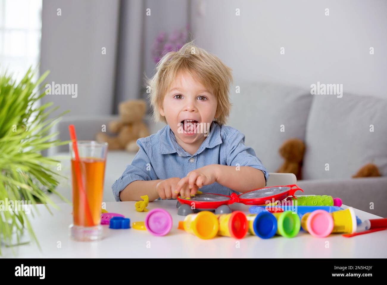 Cute blond child, sweet boy, playing with play doh modeline at home ...