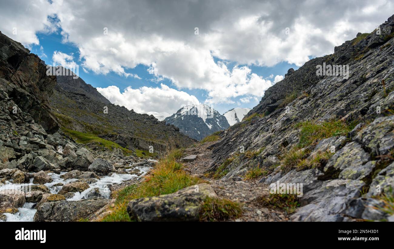 Alpine stream quickly flows under stones from high mountains with ...