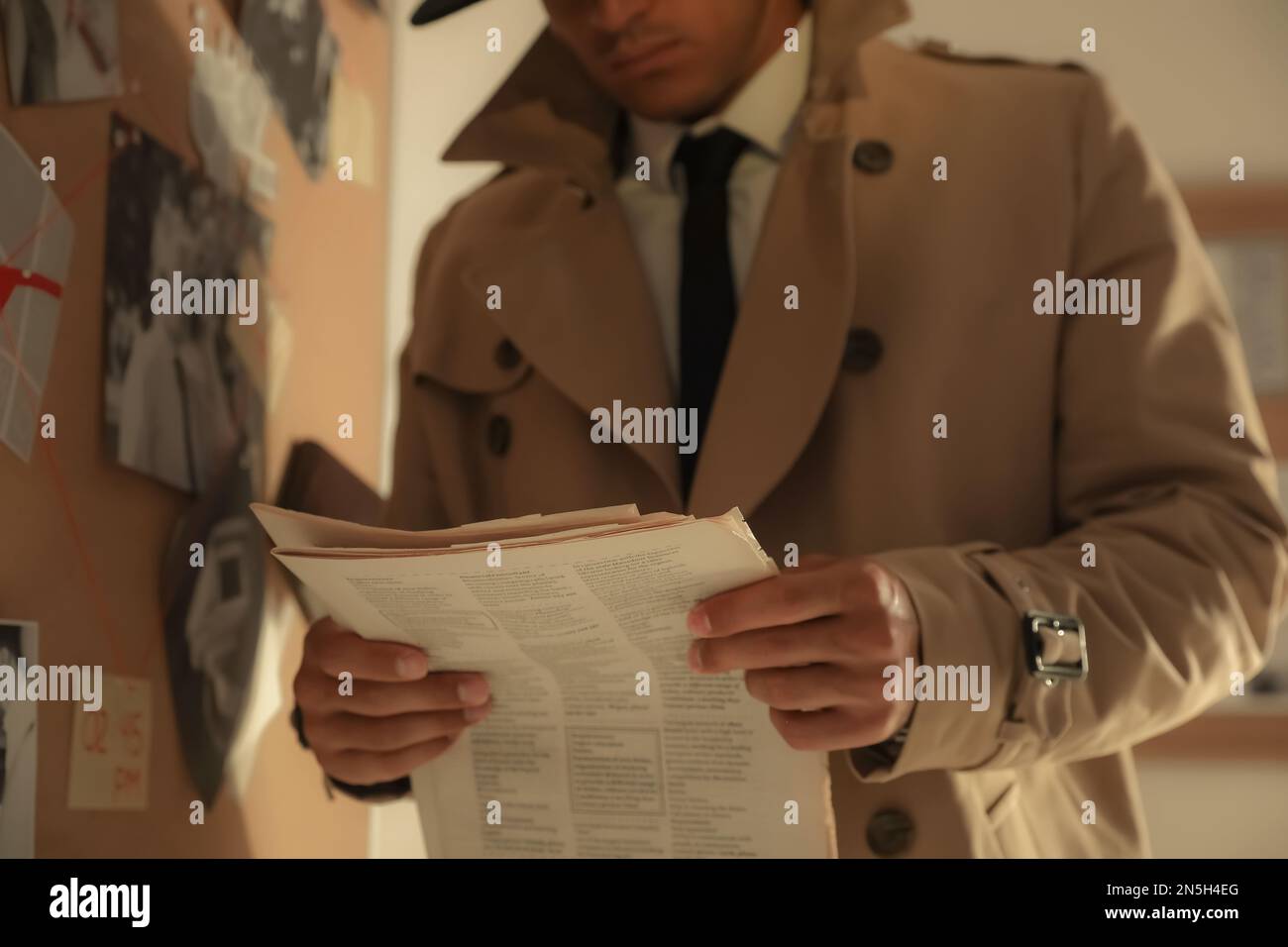 Detective with newspaper near evidence board in office, closeup Stock ...