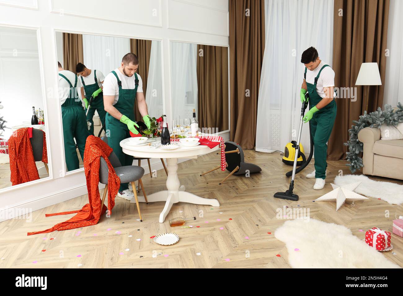 Cleaning service team working in messy room after New Year party Stock ...