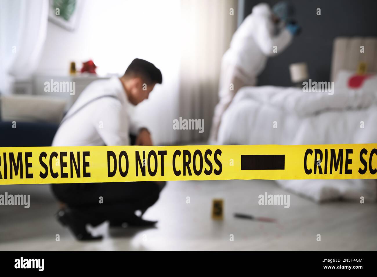 Investigators working at crime scene in messy room, focus on yellow ...