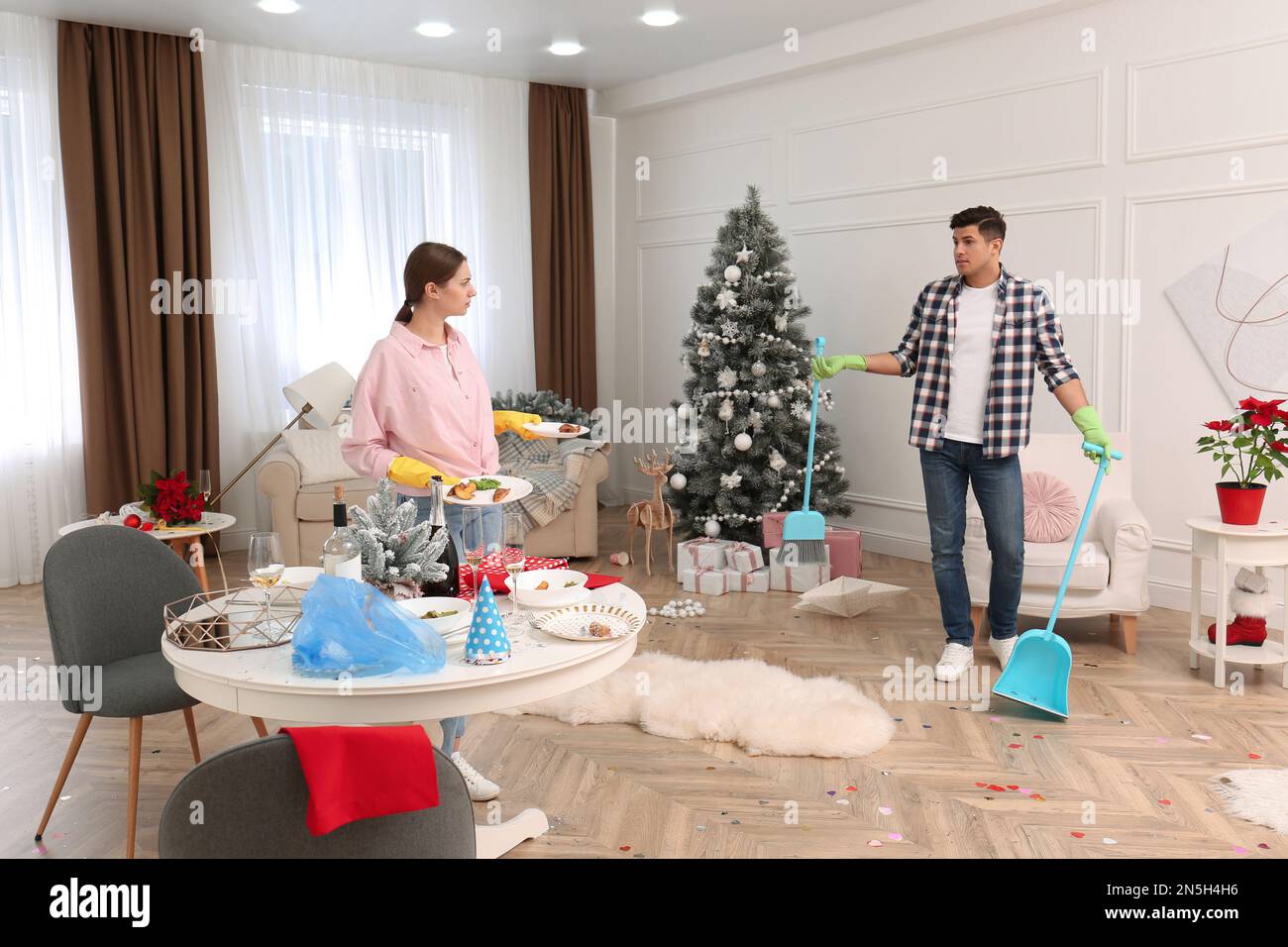 Couple cleaning messy room after New Year party Stock Photo - Alamy