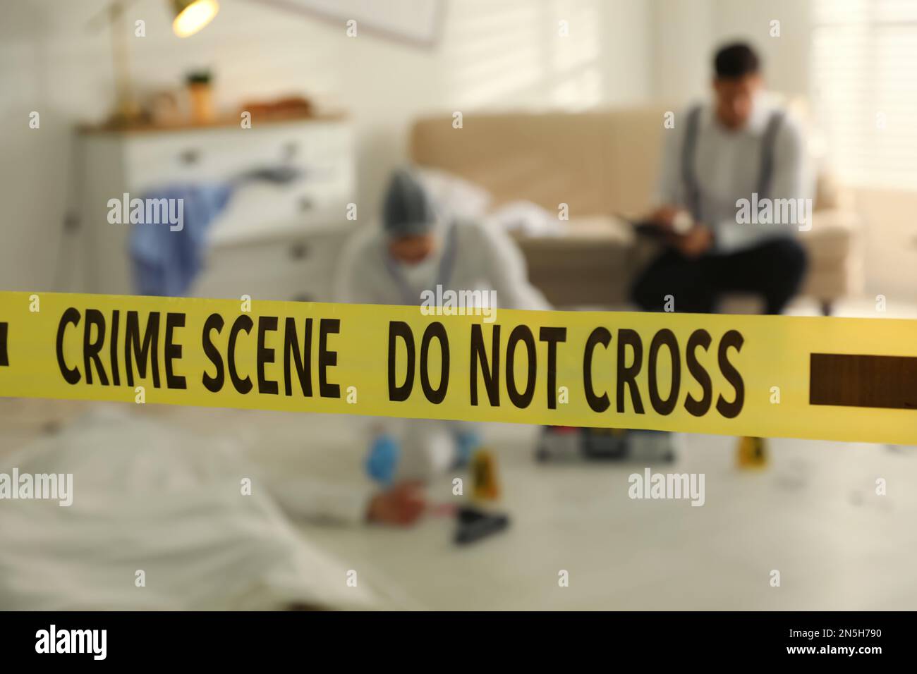Investigators working at crime scene with dead body, focus on yellow ...