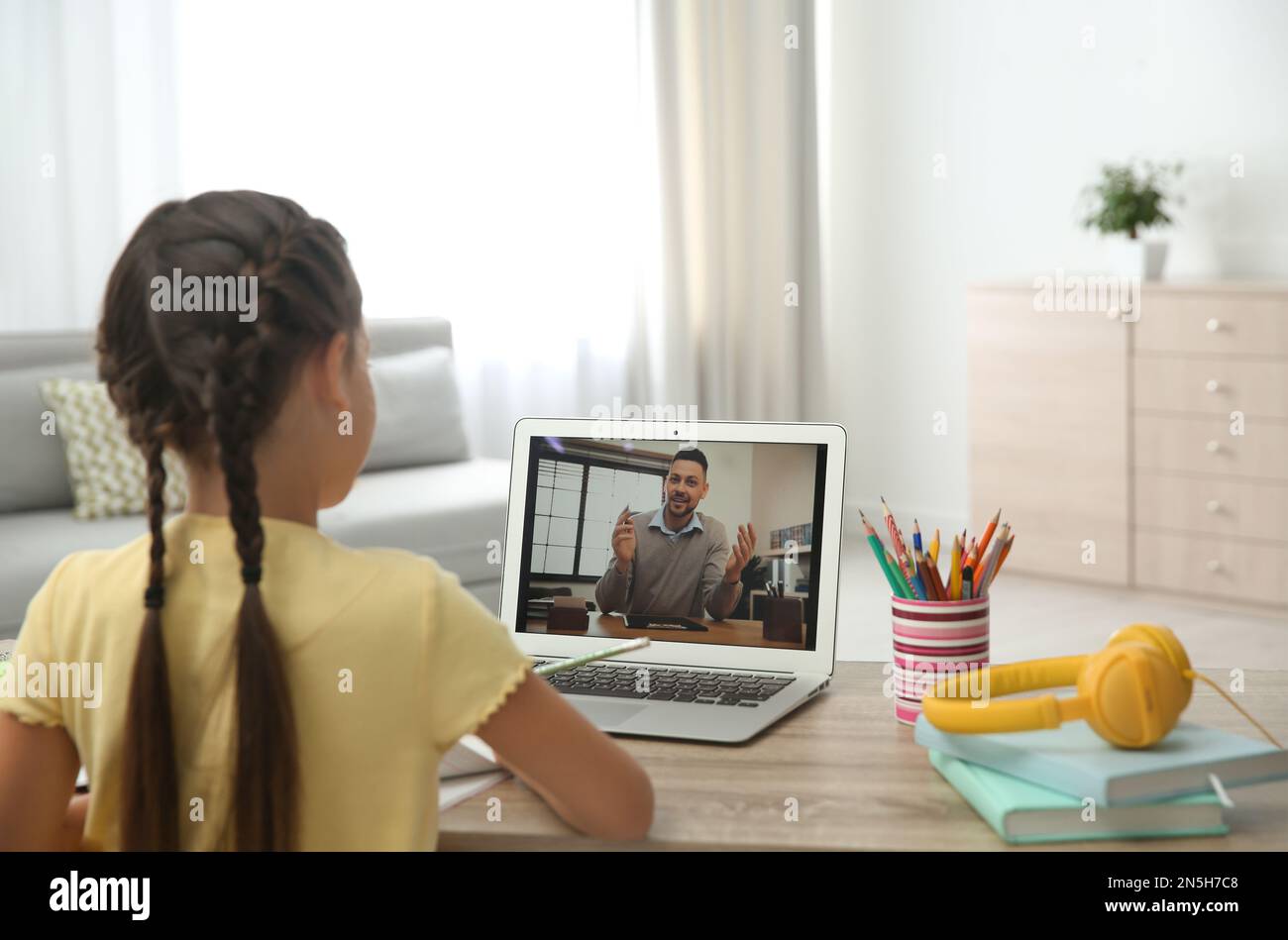 Distance learning, studying at home. Girl having online school lesson with teacher during ...