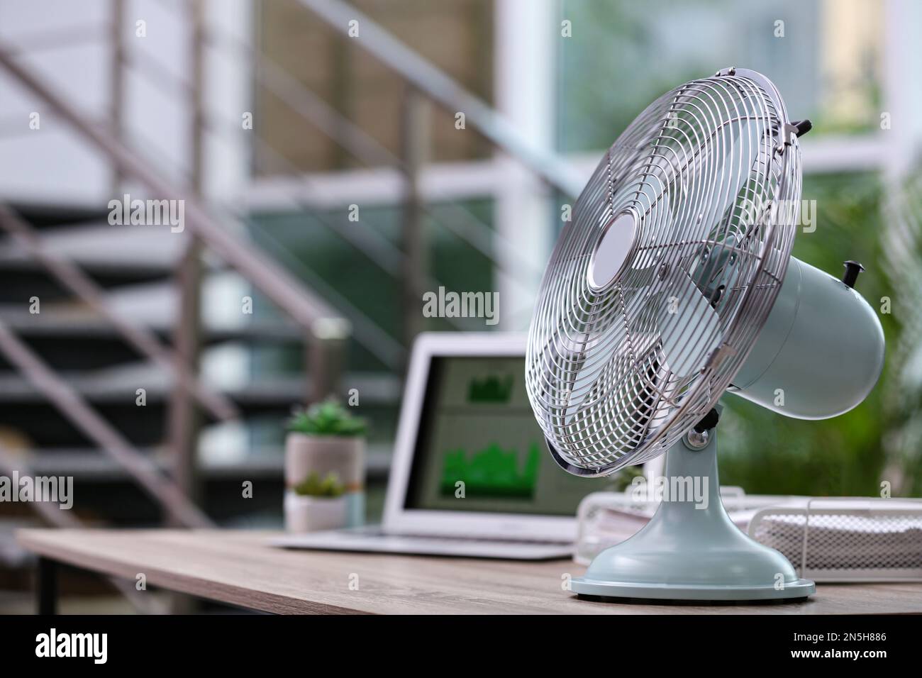 Modern electric fan on table in office. Space for text Stock Photo - Alamy