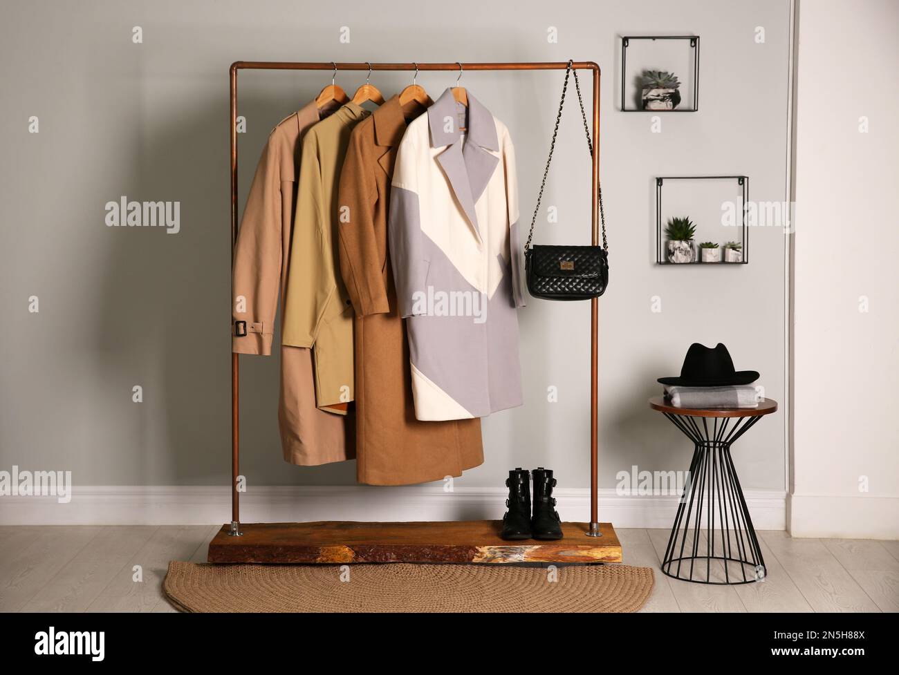 Different warm coats on rack in stylish room interior Stock Photo - Alamy