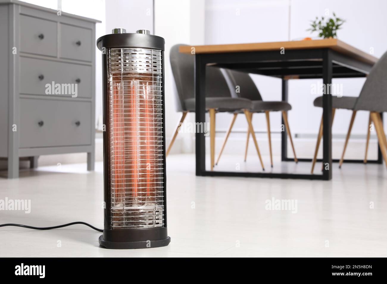 Modern electric heater on floor at home. Space for text Stock Photo - Alamy