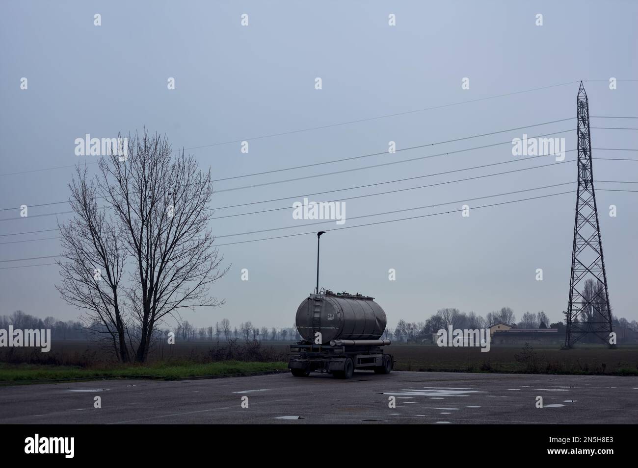 Tank in a parking lot by the edge of a fields with a pylon on a cloudy ...