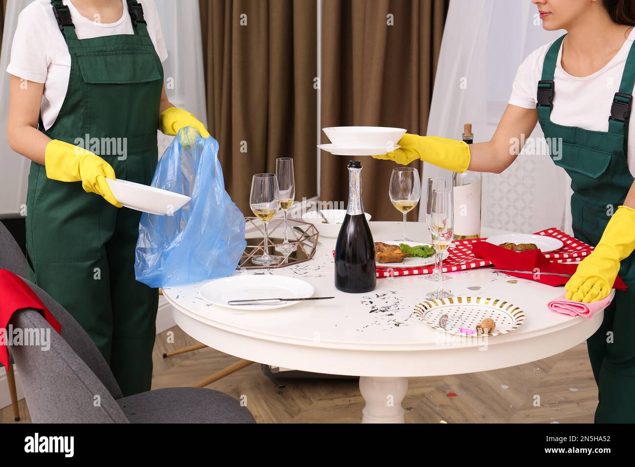 Cleaning service team working in messy room after New Year party Stock ...
