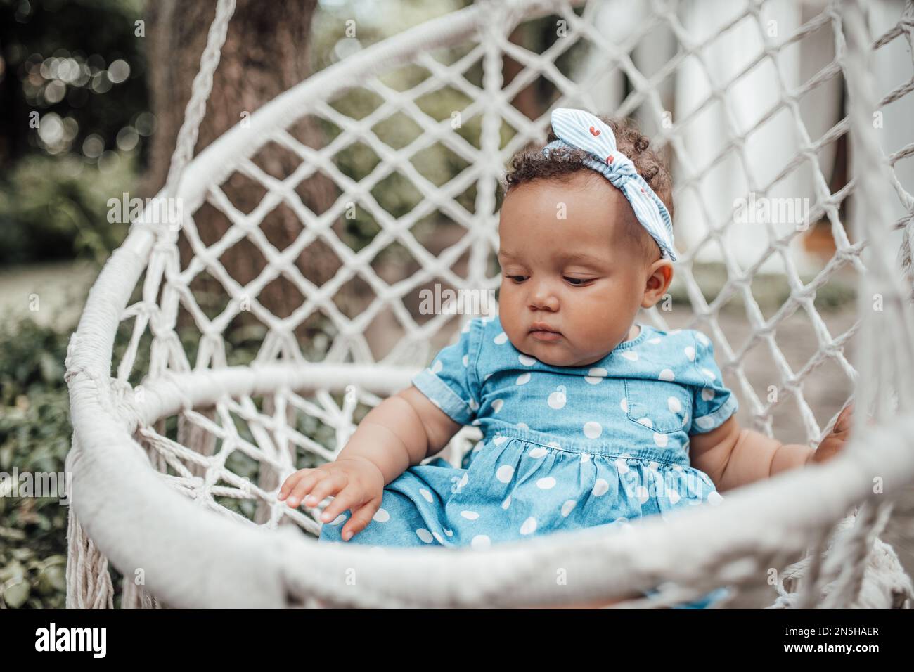 Swarthy little girl in blue polka dot dress has positive emotion ...