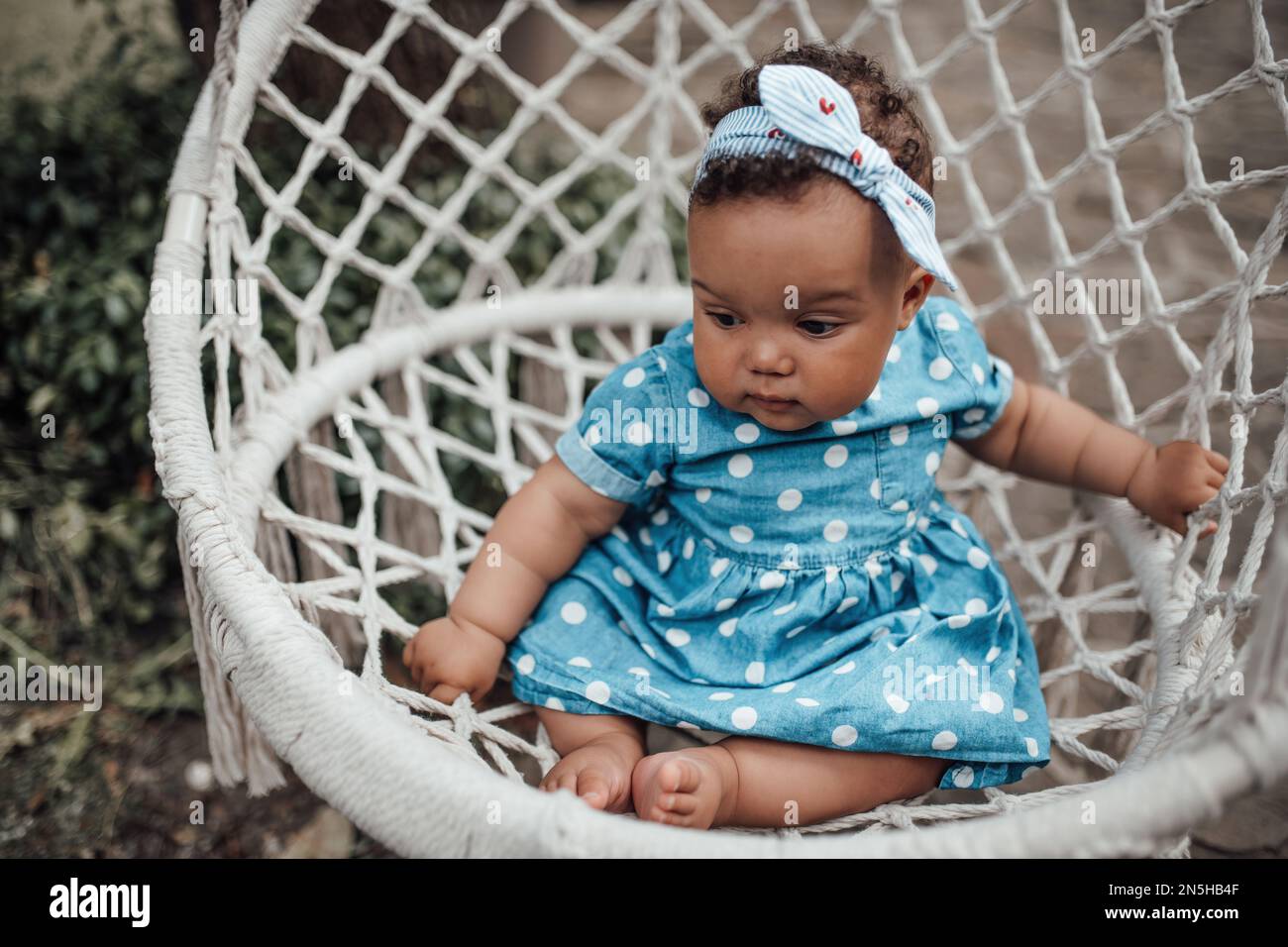 Swarthy little girl in blue polka dot dress has positive emotion ...