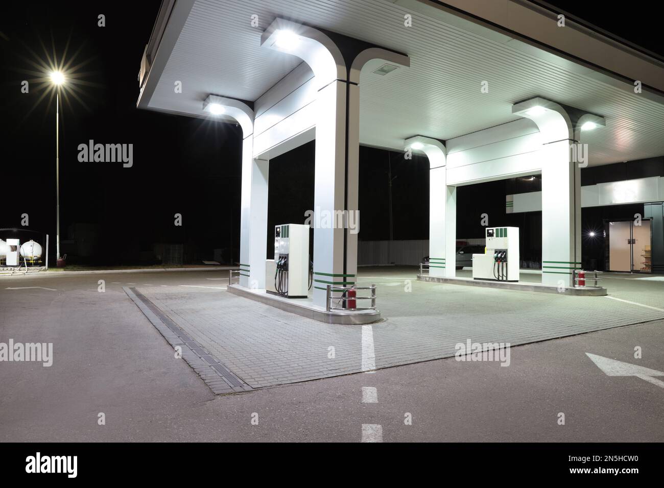 Modern gas station with convenience store beside the road at night ...