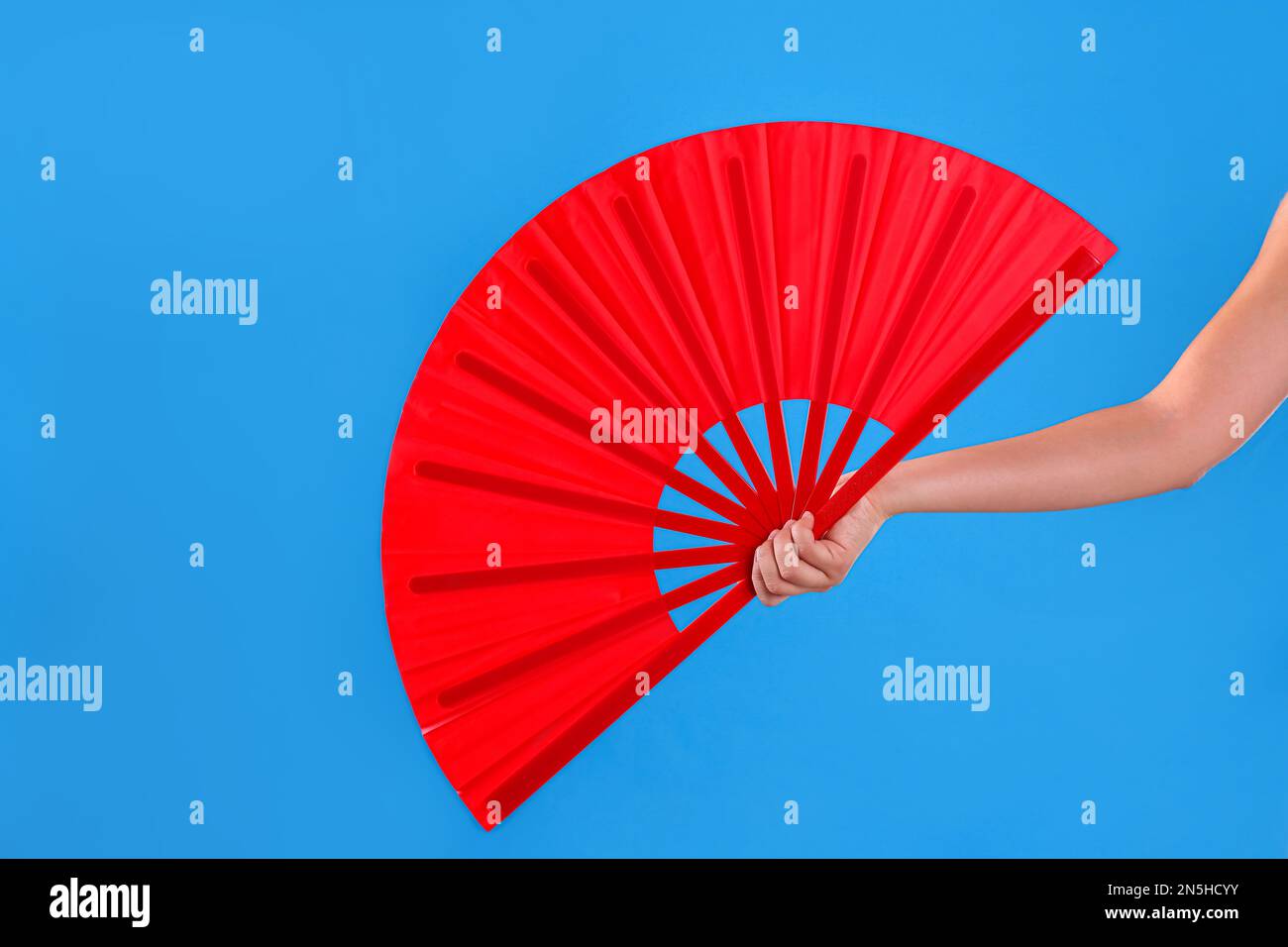Woman holding red hand fan on light blue background, closeup Stock ...