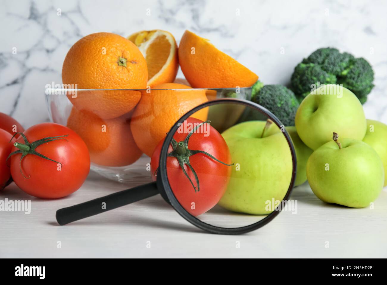 Fresh fruits, vegetables and magnifying glass on white table. Poison ...