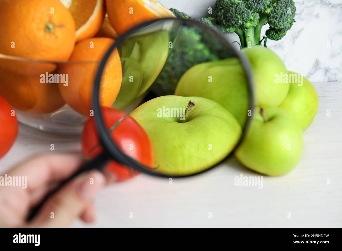 Woman with magnifying glass exploring vegetables and fruits, closeup ...
