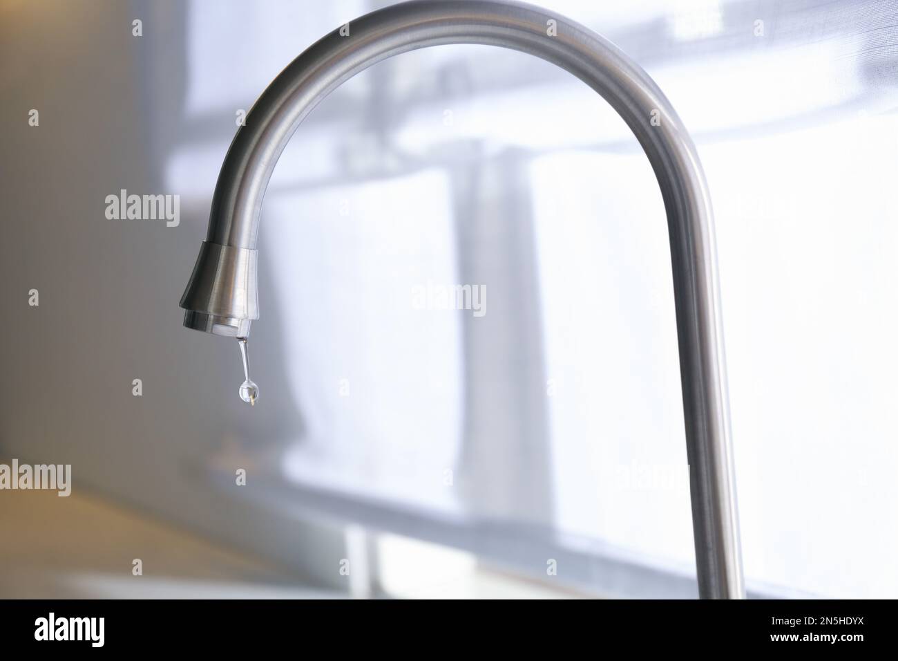 Water drop falling down from tap on blurred background, closeup Stock ...