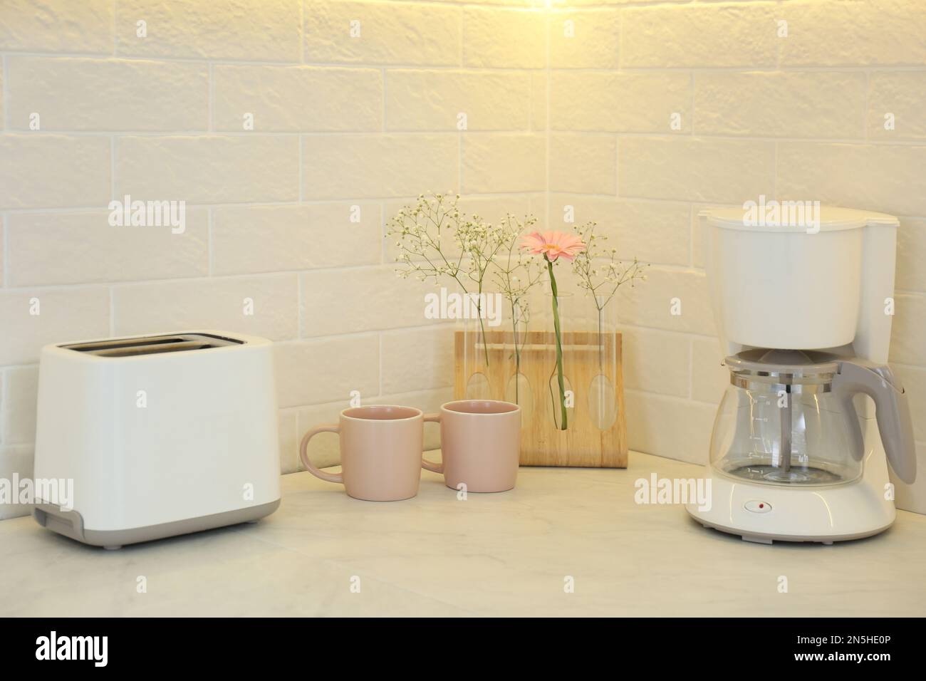 Modern toaster, cups, flowers and coffee machine on counter in kitchen Stock Photo - Alamy