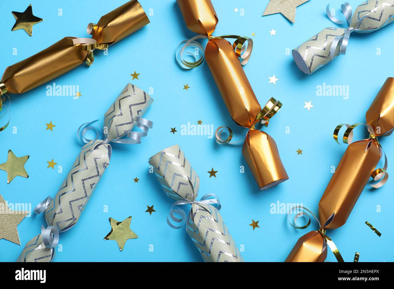 Christmas crackers and shiny confetti on light blue background, flat ...