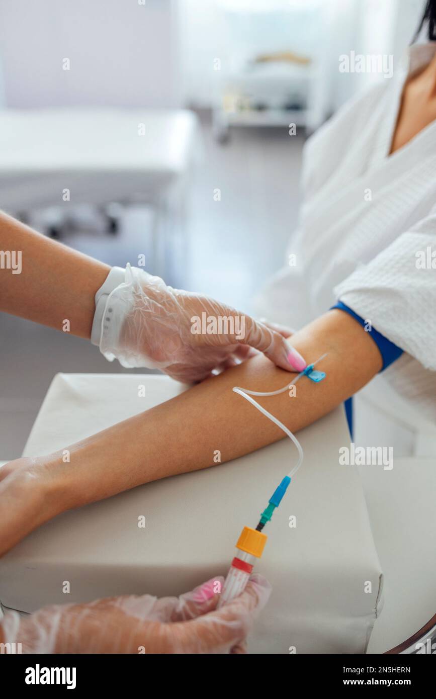Young brunette woman in a white coat makes medical procedures. A nurse ...