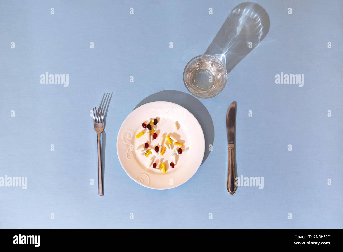 Tablets, pills and capsules on a white porcelain plate. The table is ...