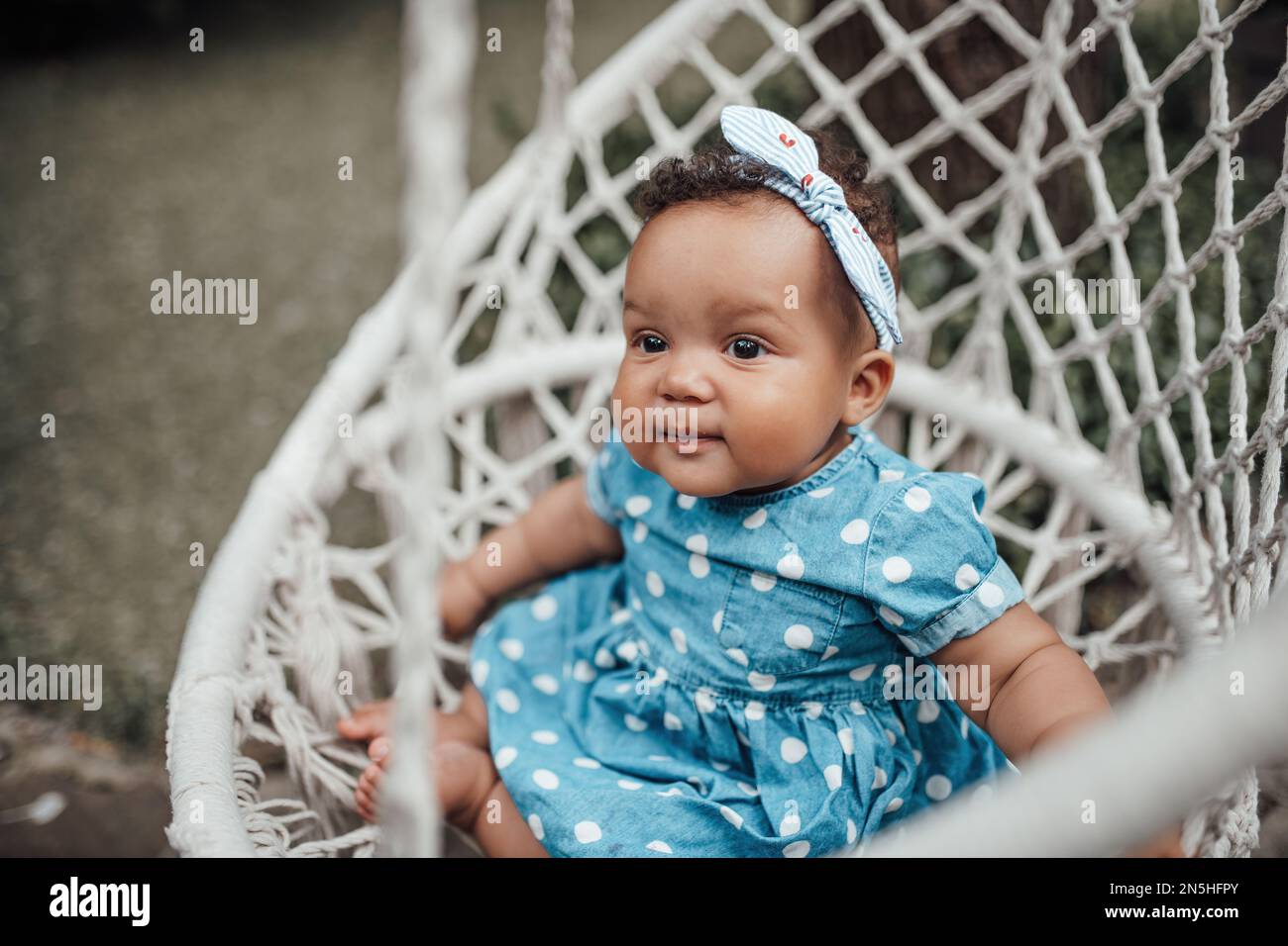 Swarthy little girl in blue polka dot dress has positive emotion ...