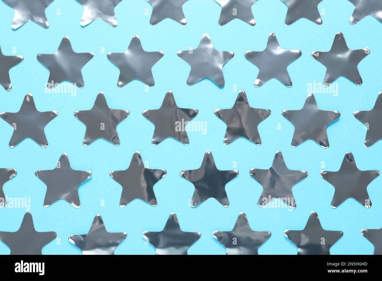 Shiny silver star shaped confetti on light blue background, flat lay ...