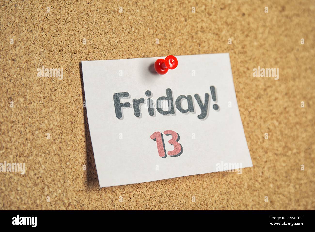 Paper note with phrase Friday! 13 pinned to cork background. Bad luck ...