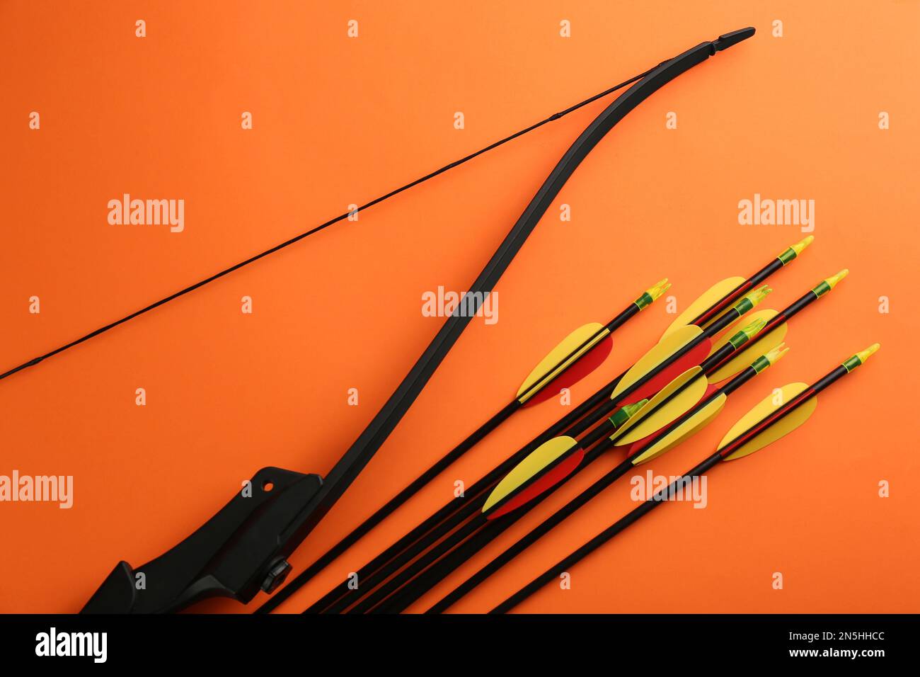Black bow and set of arrows on orange background, flat lay. Archery ...