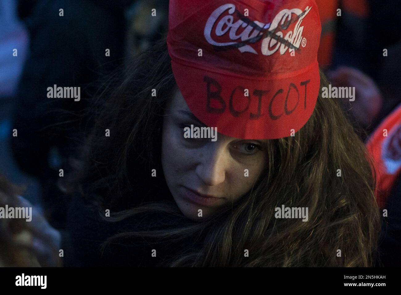 A protestor wears a Coca-Cola hat reading " Boycott" during a ...