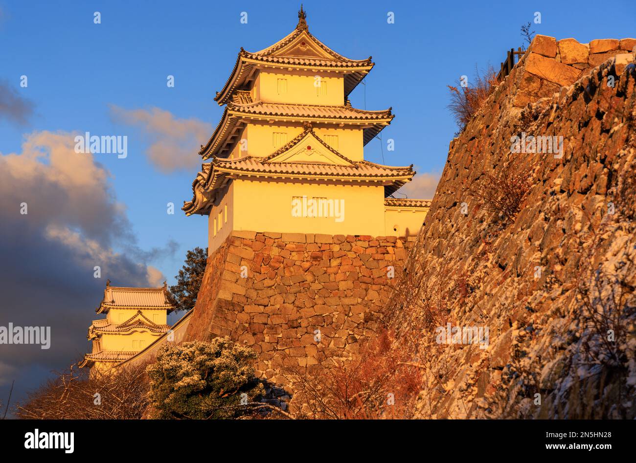 Golden hour light hits ancient Japanese castle atop stone wall Stock ...
