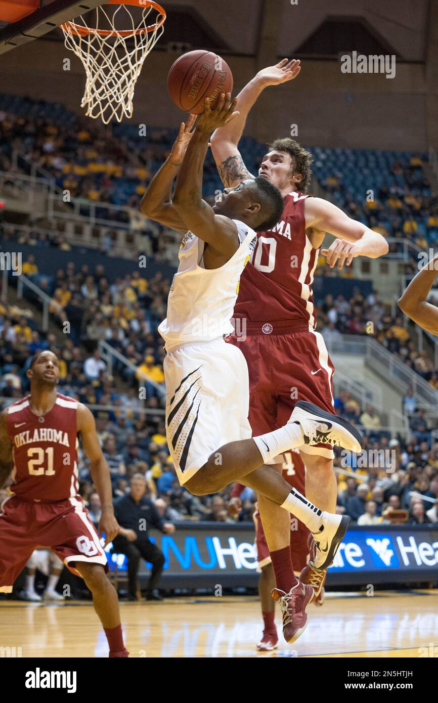West Virginia's Juwan Staten, left, drives by Oklahoma's Ryan Spangler ...