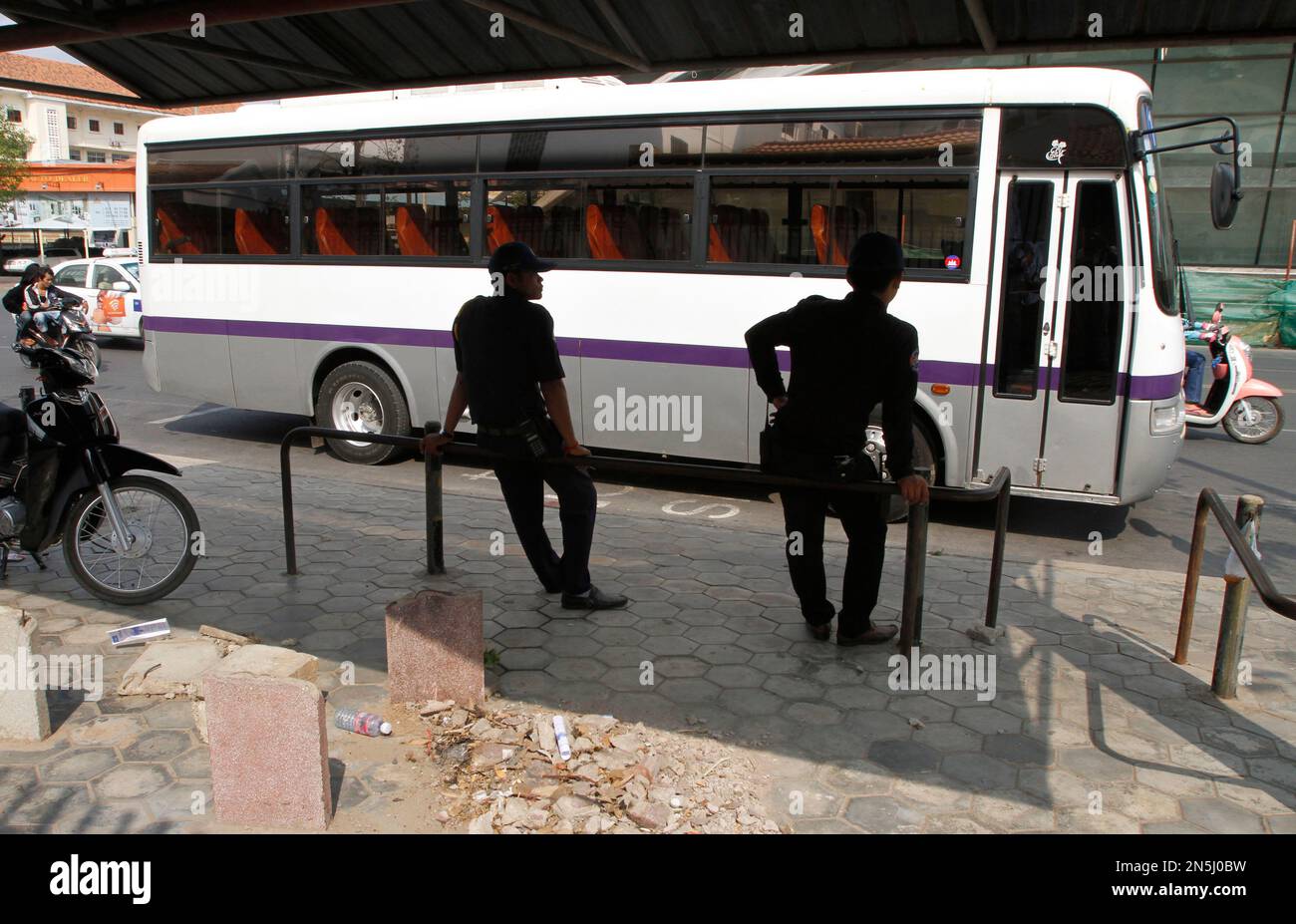 Security guards stand at a bus stop as Phnom Penh begins its trial for ...