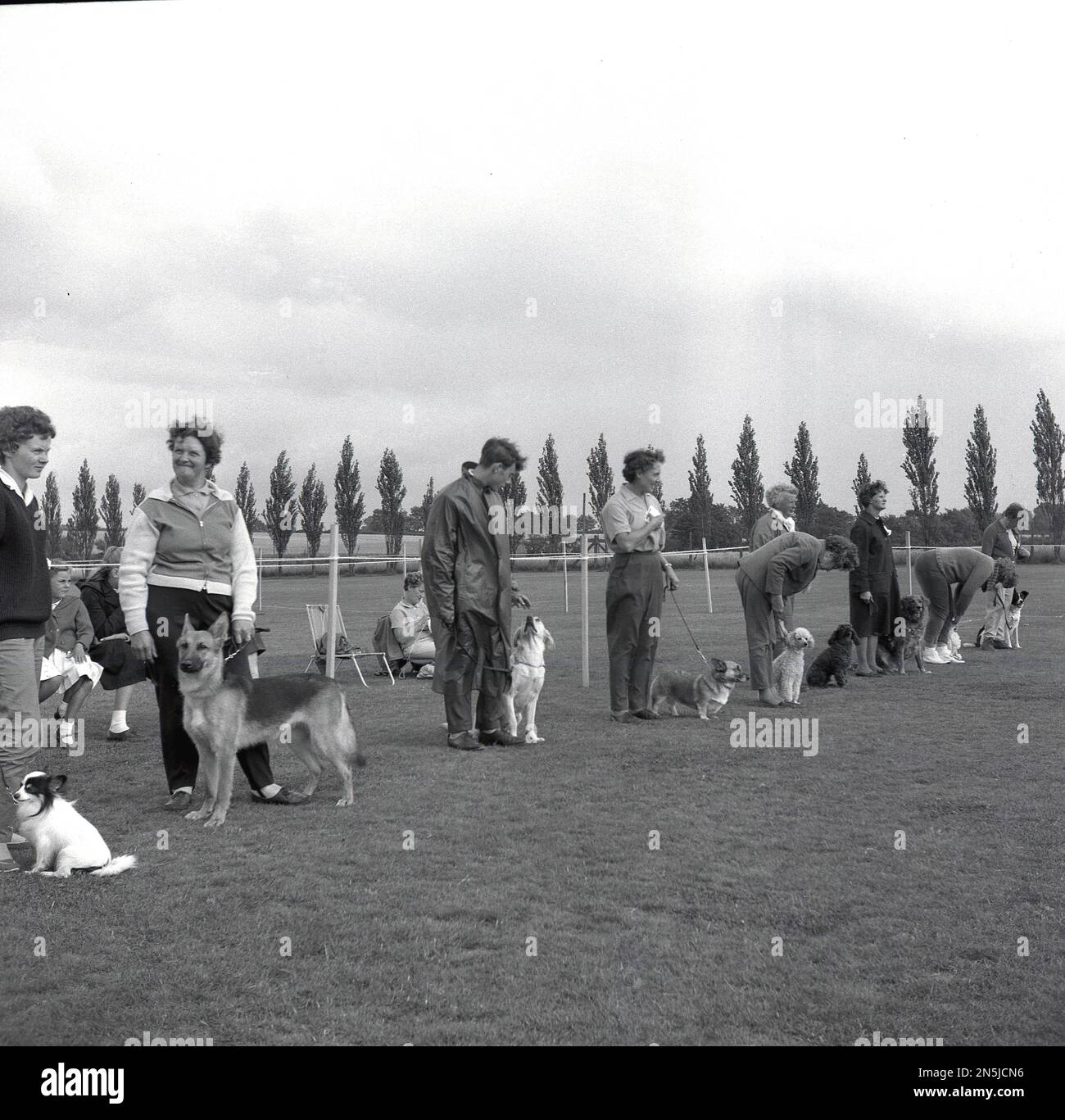 1963, historical, outside in a large field, several owners standing in ...