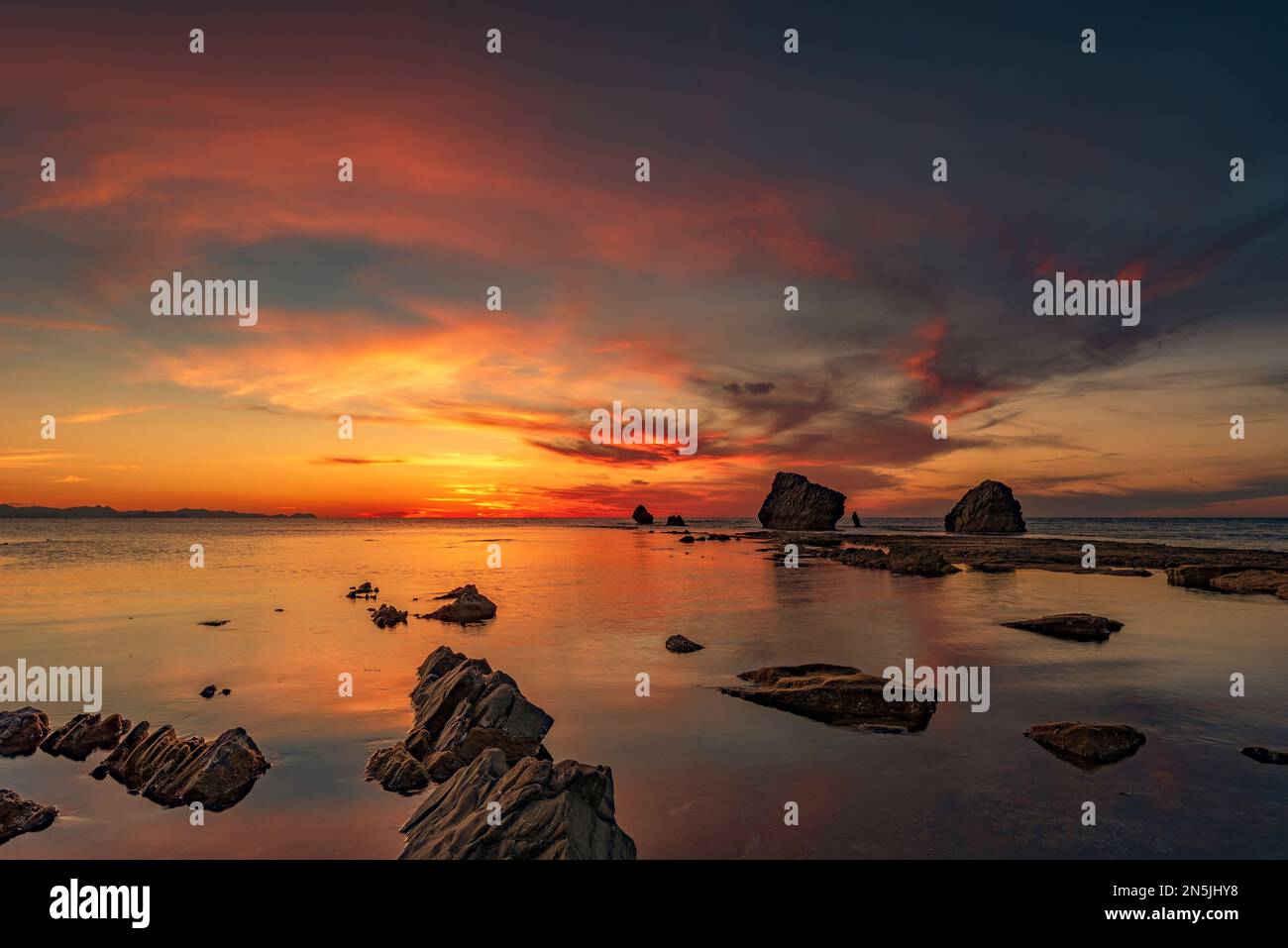 The sun sets behind the rocks of Settefrati beach, Sicily Stock Photo ...