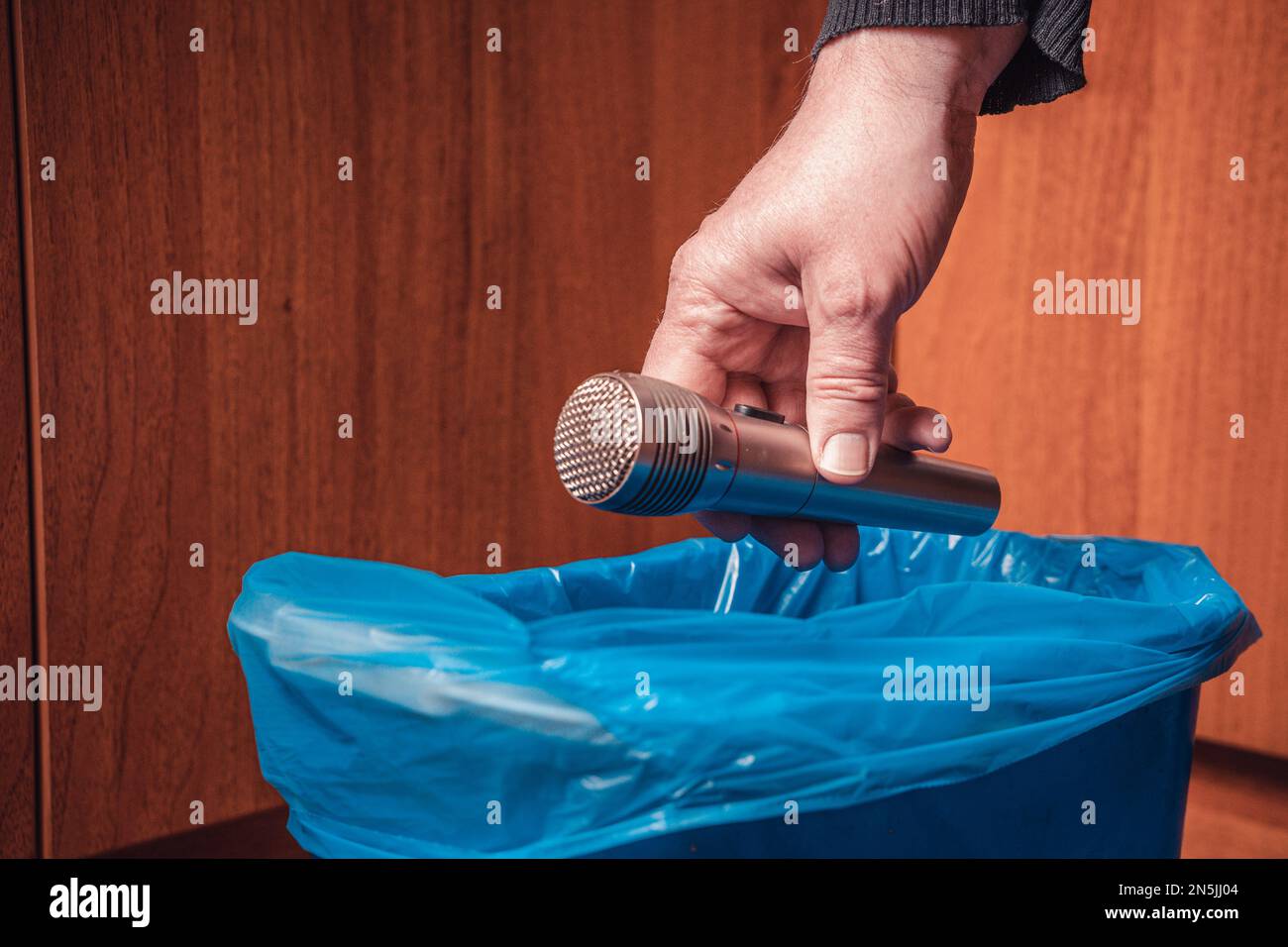 The man throws the microphone in the trash. Man's hand with a ...