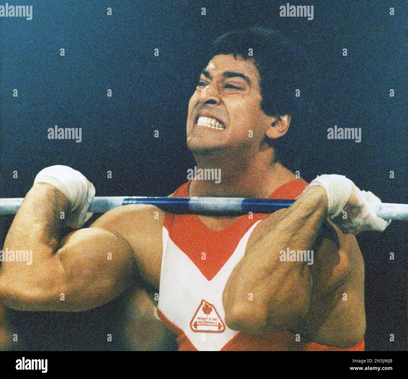 Canadian weightlifter Paramajit Gill grits his teeth and strains as his ...
