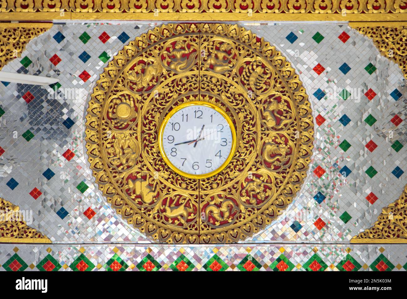 Golden clock on the decorative wall of a Buddhist temple, Thailand ...