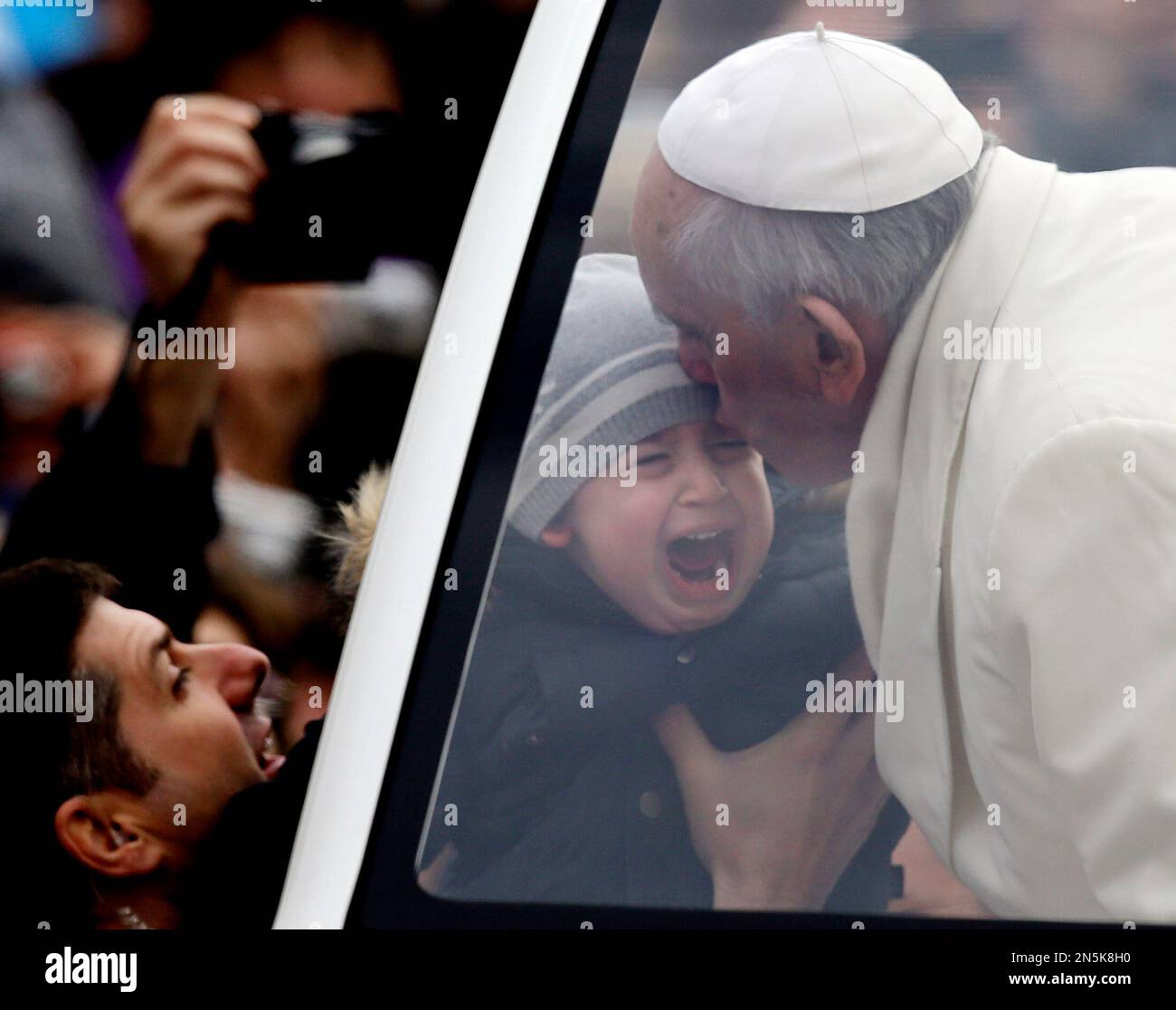 Pope Francis kisses a crying child during his tour through the crowd in ...