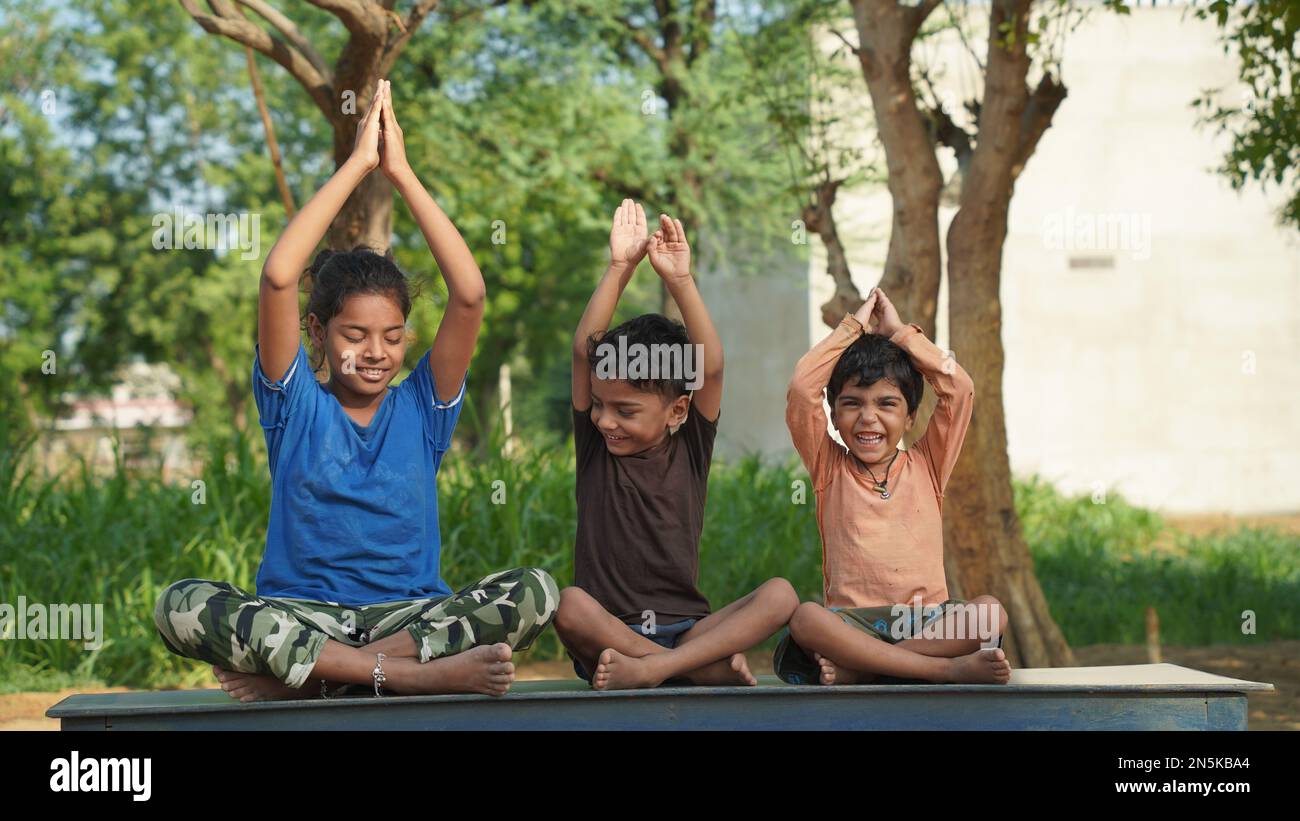 Two Indian little girl and a boy doing meditate yoga asana on roll mat ...