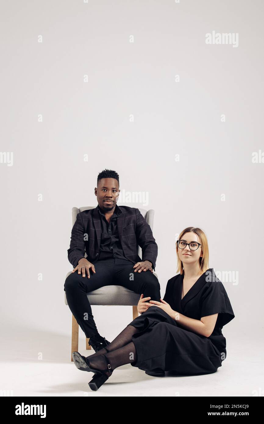 Young interracial couple sits in room against white background. Concept ...