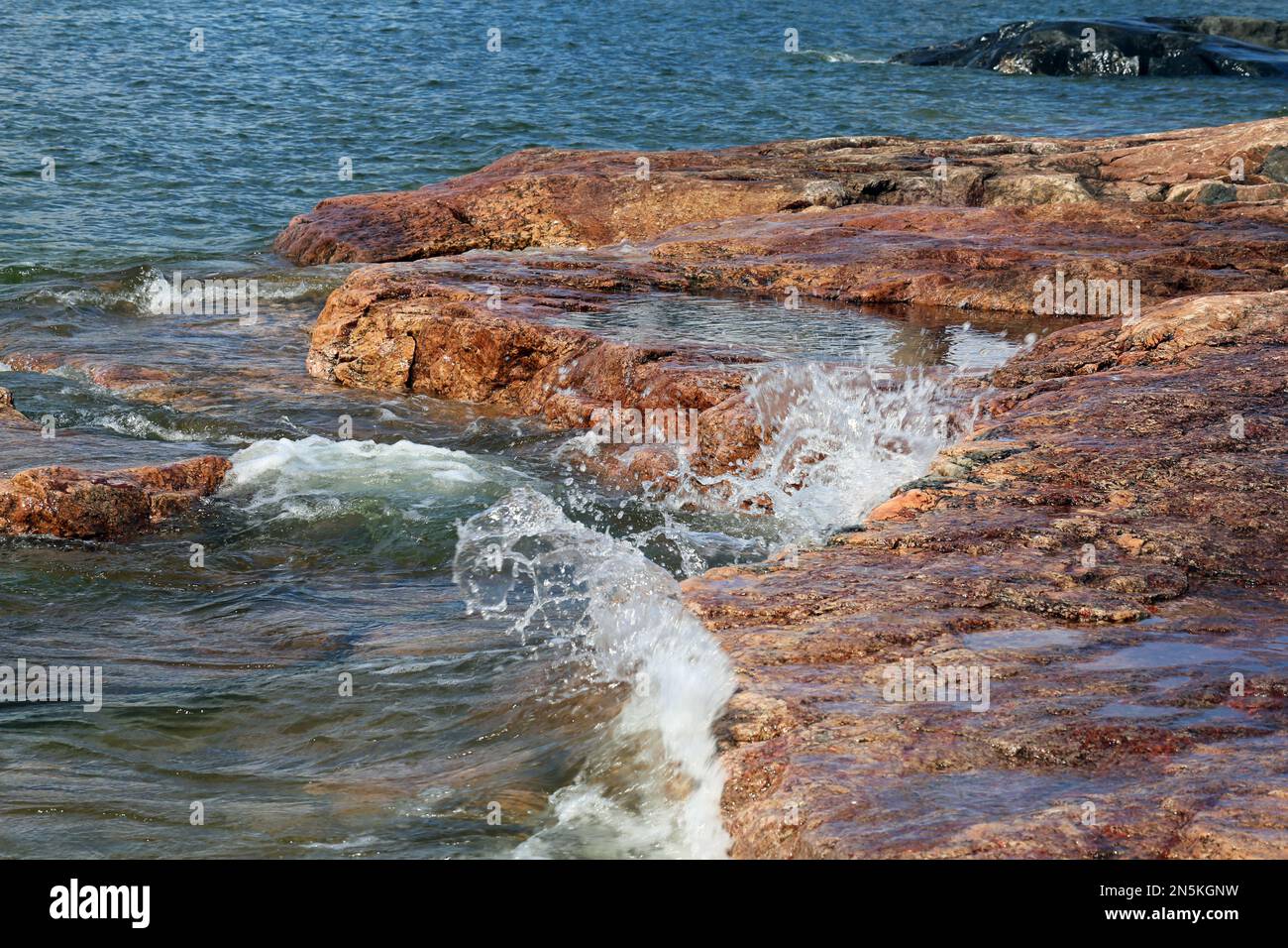 Lots of small waves hitting red and black beach rocks in Eira aka ...