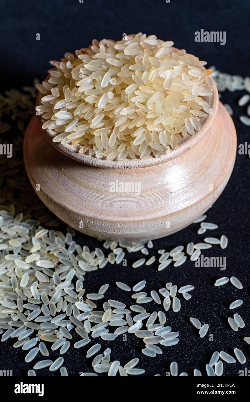 Portrait view of white rice in a wooden bowl isolated on a black ...