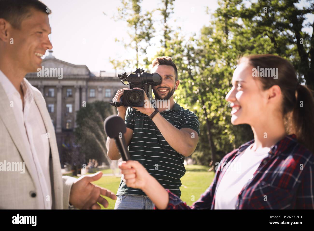 Professional journalist and operator with video camera taking interview ...