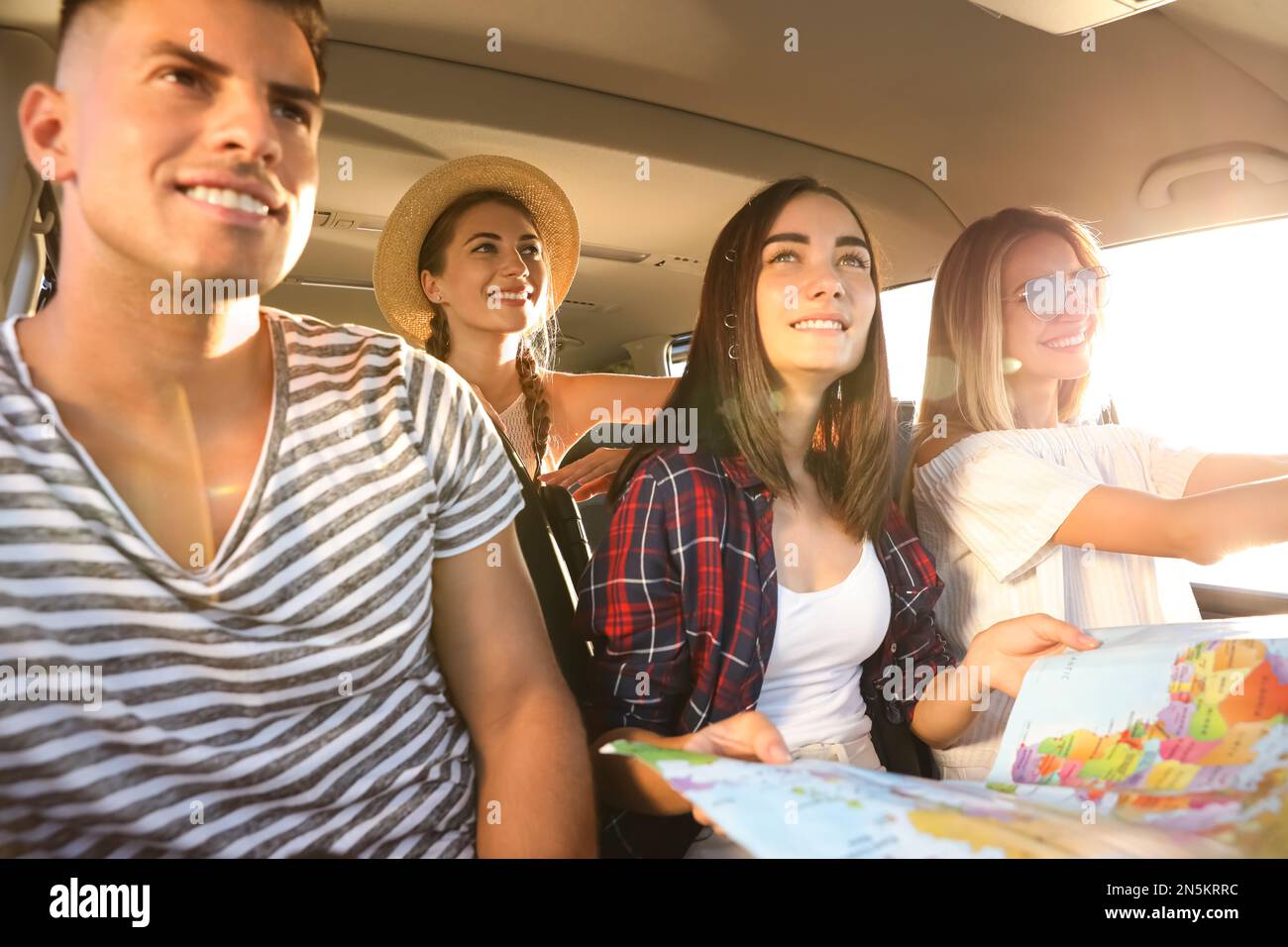 Happy friends with map in car on road trip Stock Photo - Alamy