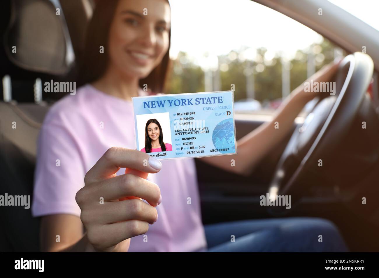 Happy young woman holding license while sitting in car, focus on hand ...
