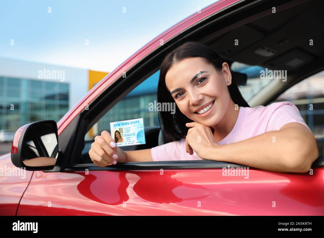 Happy young woman holding license while sitting in car. Driving school ...
